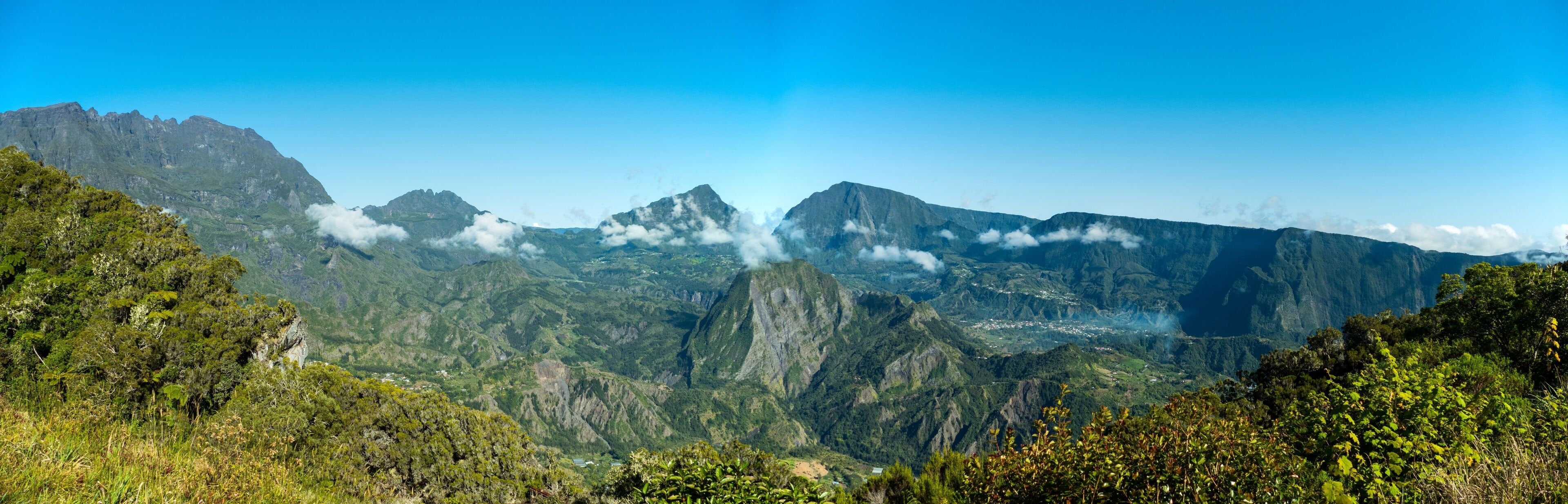 Paisagem montanhosa com vegetação exuberante e céu azul límpido.