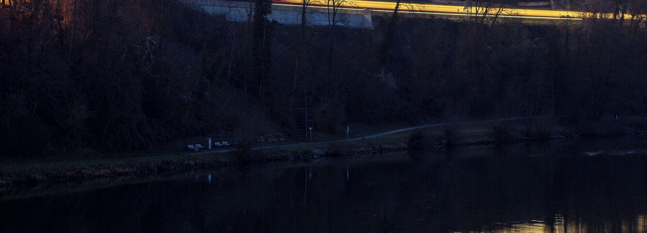 Bad Wimpfen: die Altstadt von Wimpfen am Berg, Ansicht von der Neckarbrücke in der Blauen Stunde mit Weihnachtsbeleuchtung und einfahrendem Zug.
