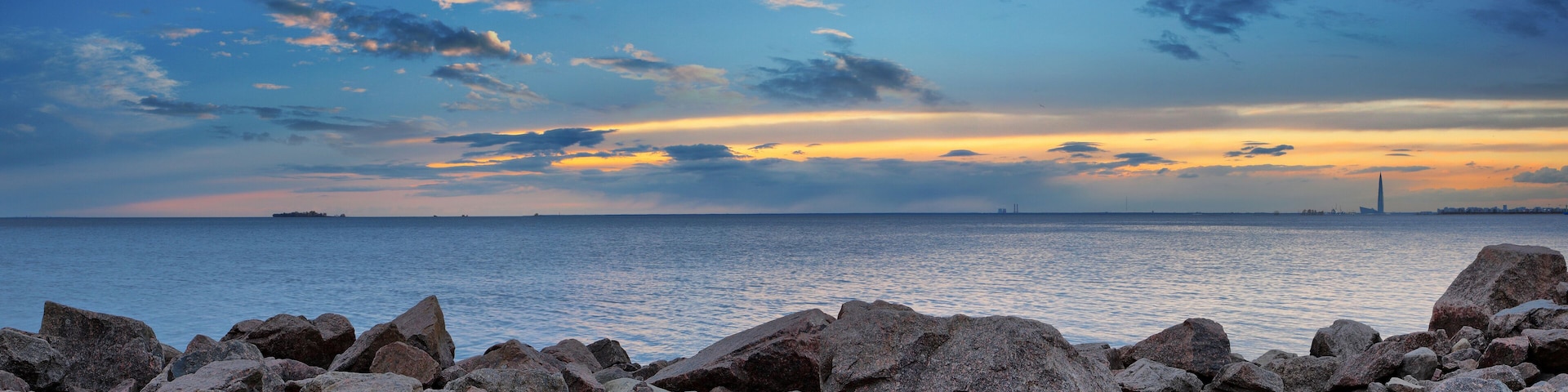 Uma costa rochosa com um pôr do sol sobre o oceano.