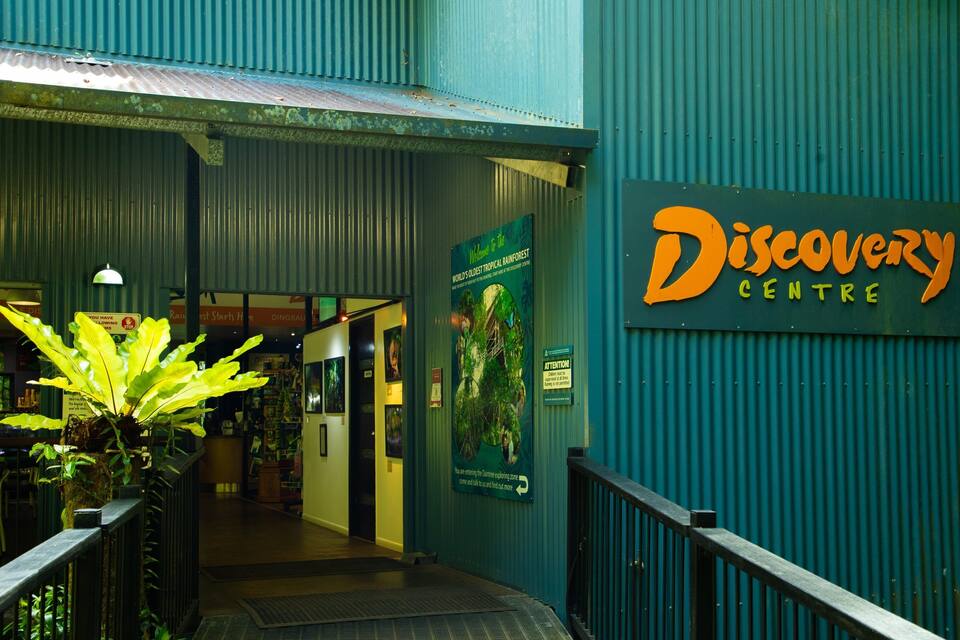 A entrada do Discovery Centre, com uma placa, uma escadaria e um vaso de planta grande.