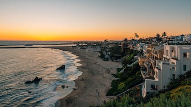 Paisagem costeira com praia, oceano e edifícios residenciais ao pôr do sol.