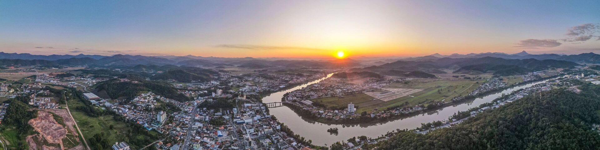 Um rio serpenteando por uma cidade rodeada por montanhas.