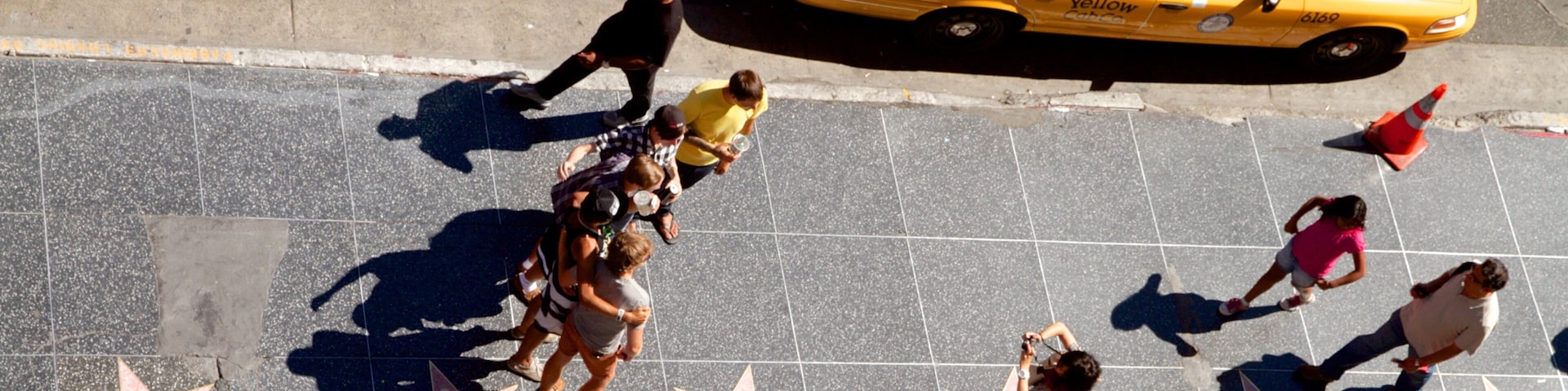 Um táxi amarelo, pedestres e as estrelas da Calçada da Fama de Hollywood.