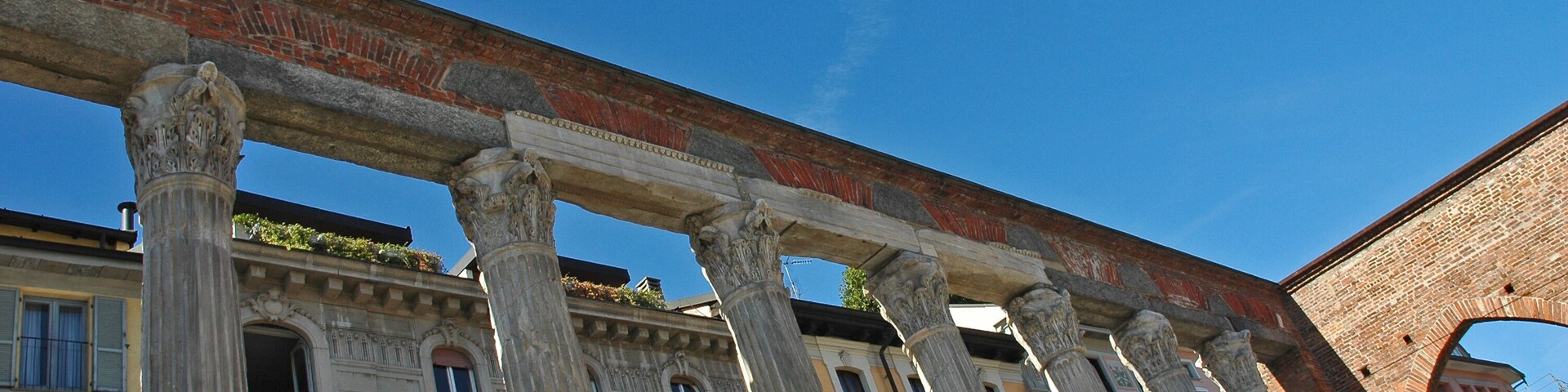 Um edifício histórico com colunas clássicas e um arco de tijolos vermelhos.