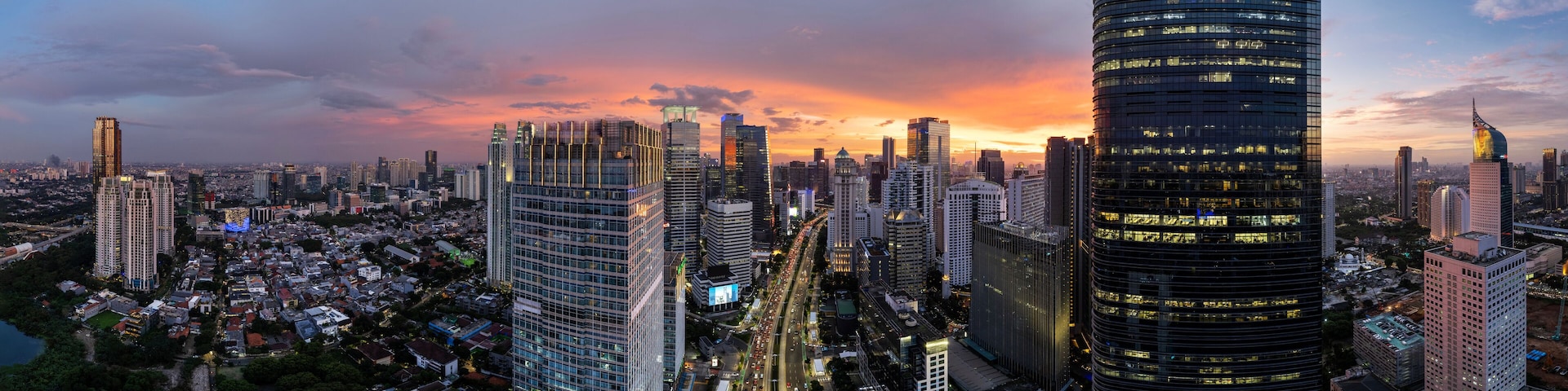 Paisagem urbana com edifícios altos, um rio e um pôr do sol.