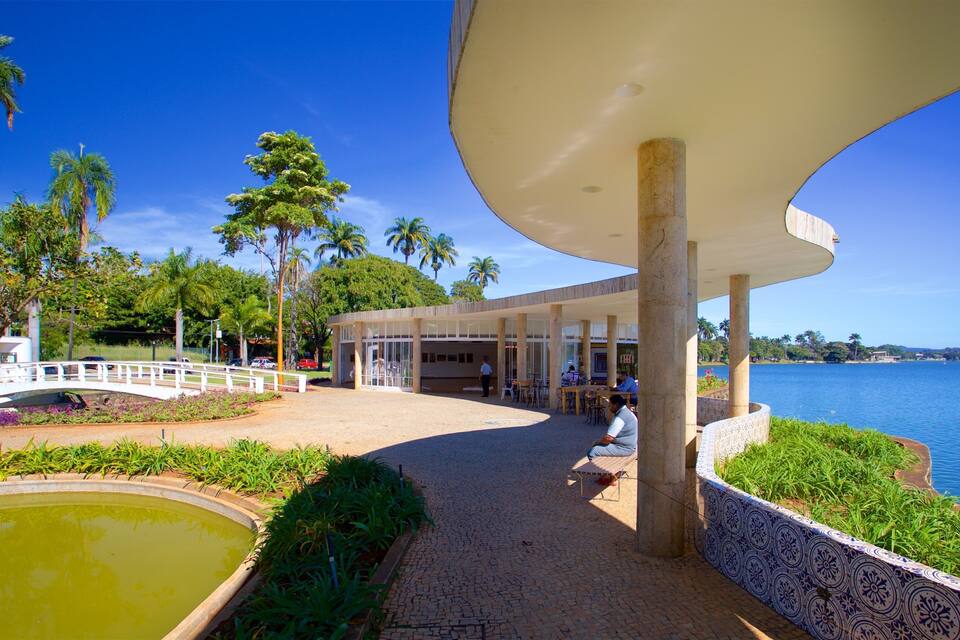 Resort à beira-mar com alpendre coberto, palmeiras, uma ponte e um corpo de água.