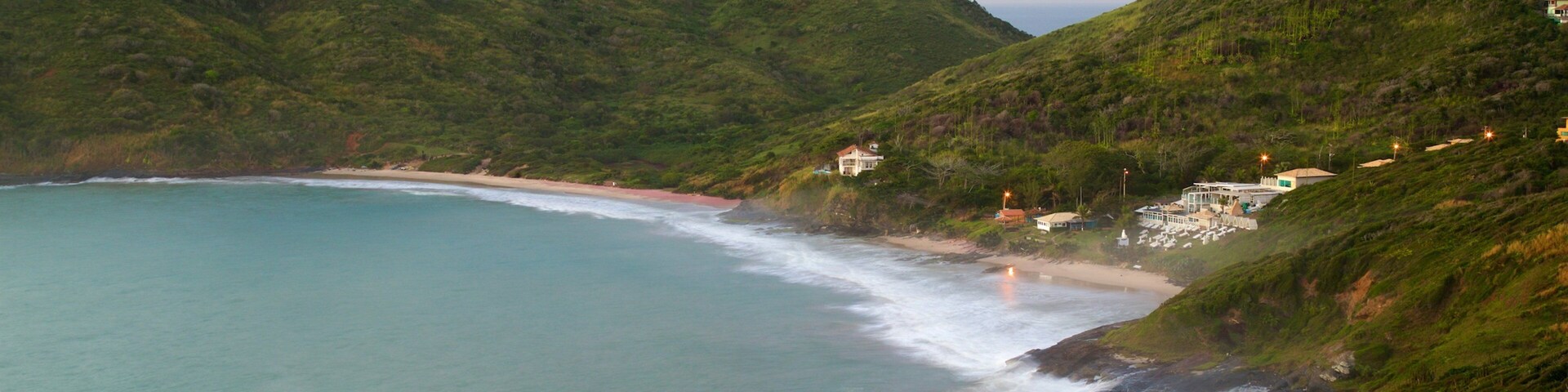 Paisagem costeira com praia, colinas e edifícios.
