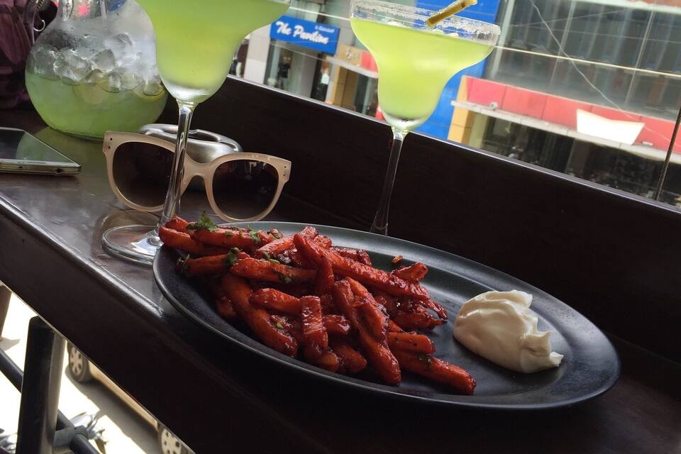 Um balcão com um prato de comida, um copo de martini e óculos de sol em uma mesa.