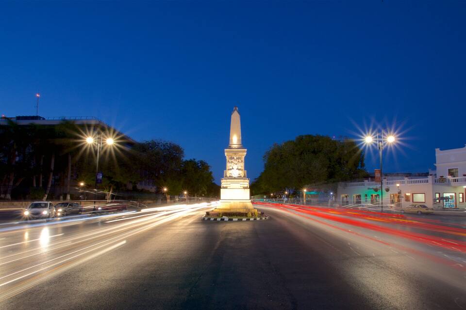 Um monumento ao entardecer com rastros de luz deixados por veículos na estrada.