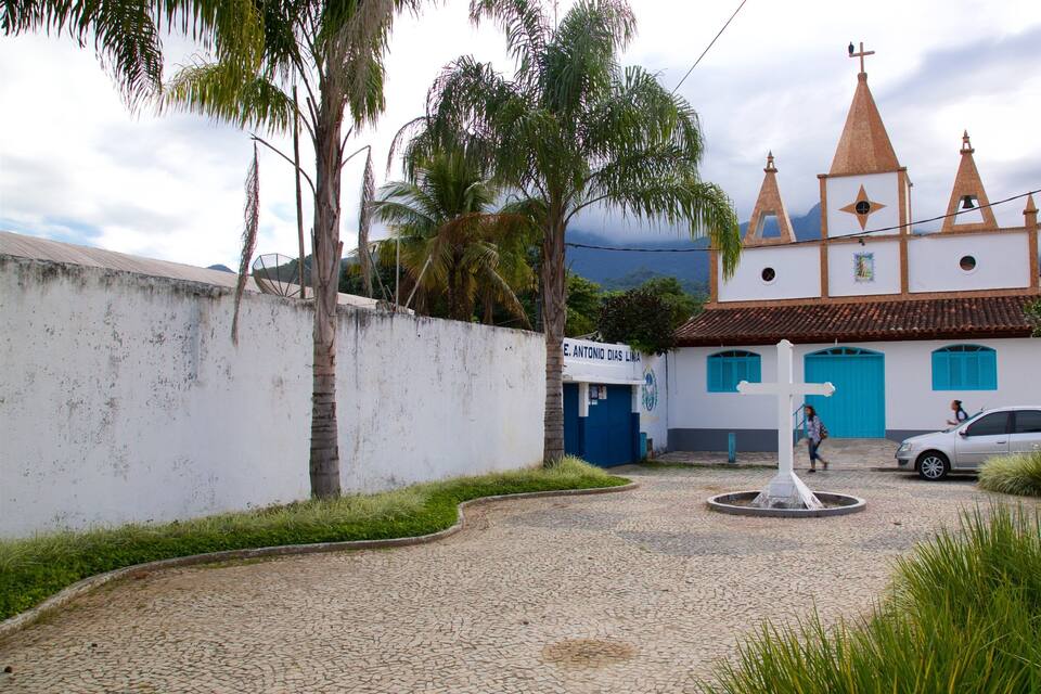 Uma igreja com cruz, palmeiras e um caminho de pedras.