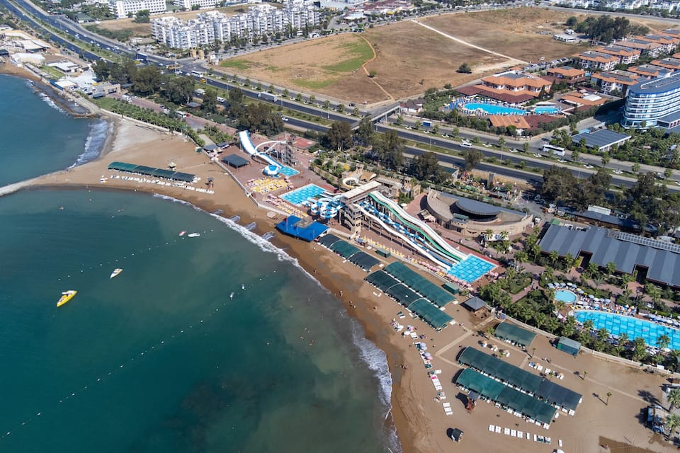 Vista aérea de um resort costeiro com praia, parque aquático e vários edifícios.