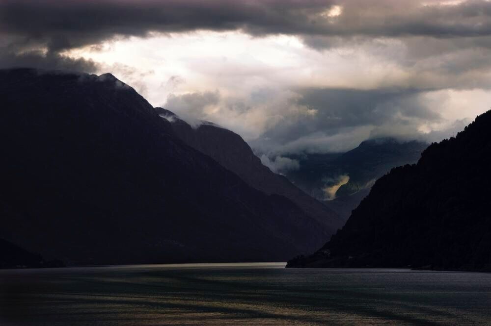 Um lago rodeado por montanhas sob um céu nublado.