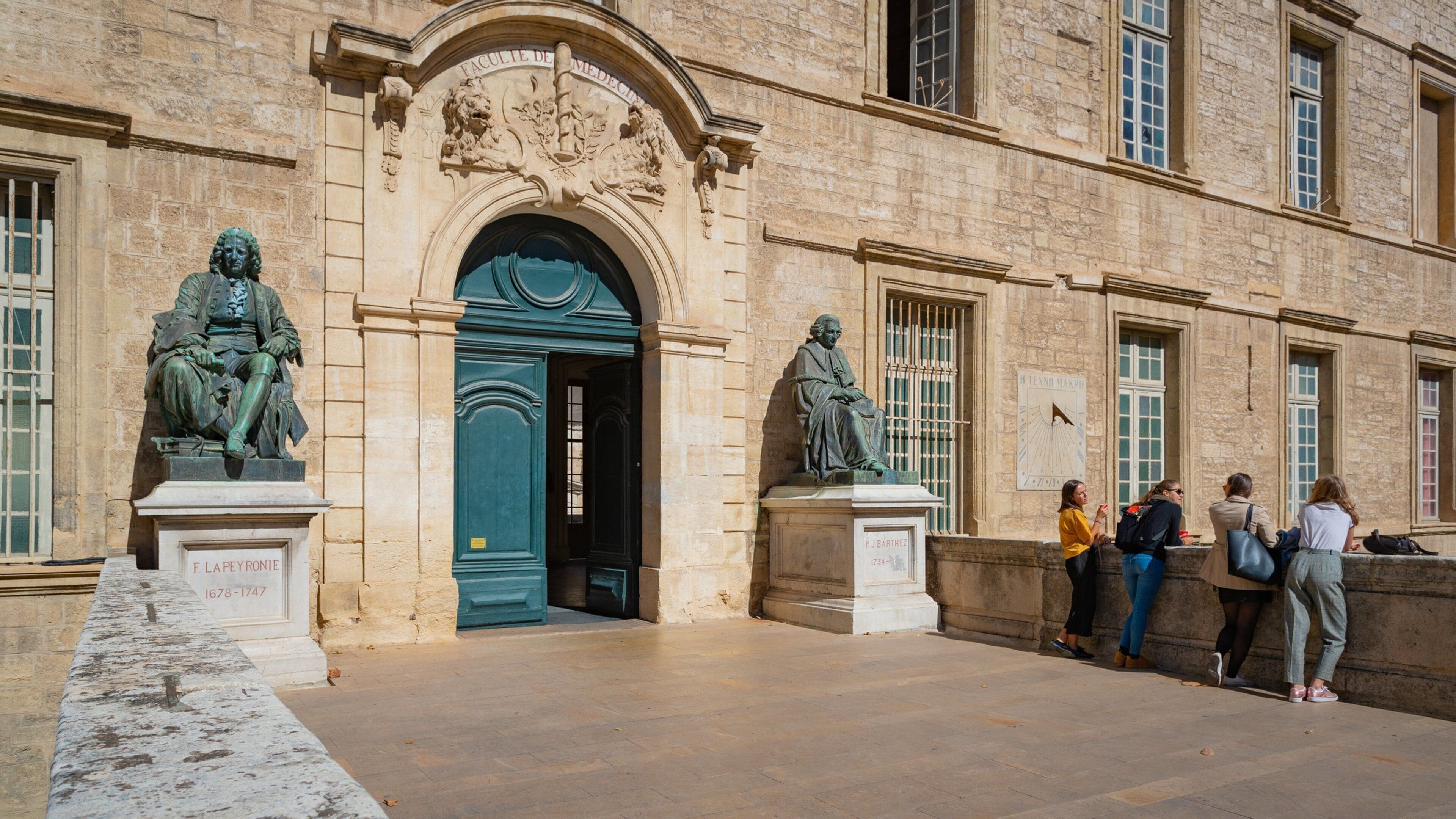 Um edifício histórico com estátuas e uma porta verde.