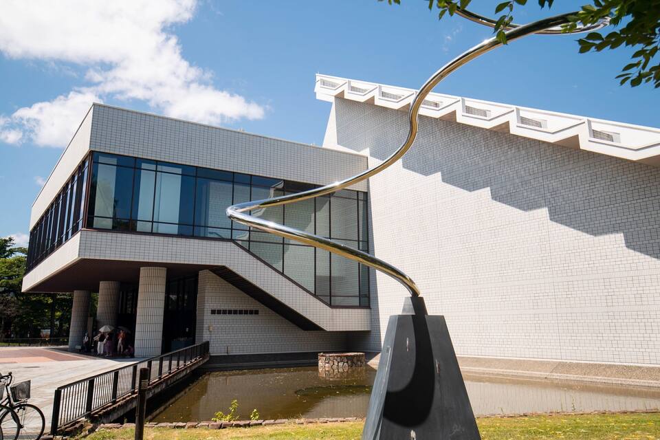 Um edifício moderno com fachada de vidro e uma escadaria espiral singular.