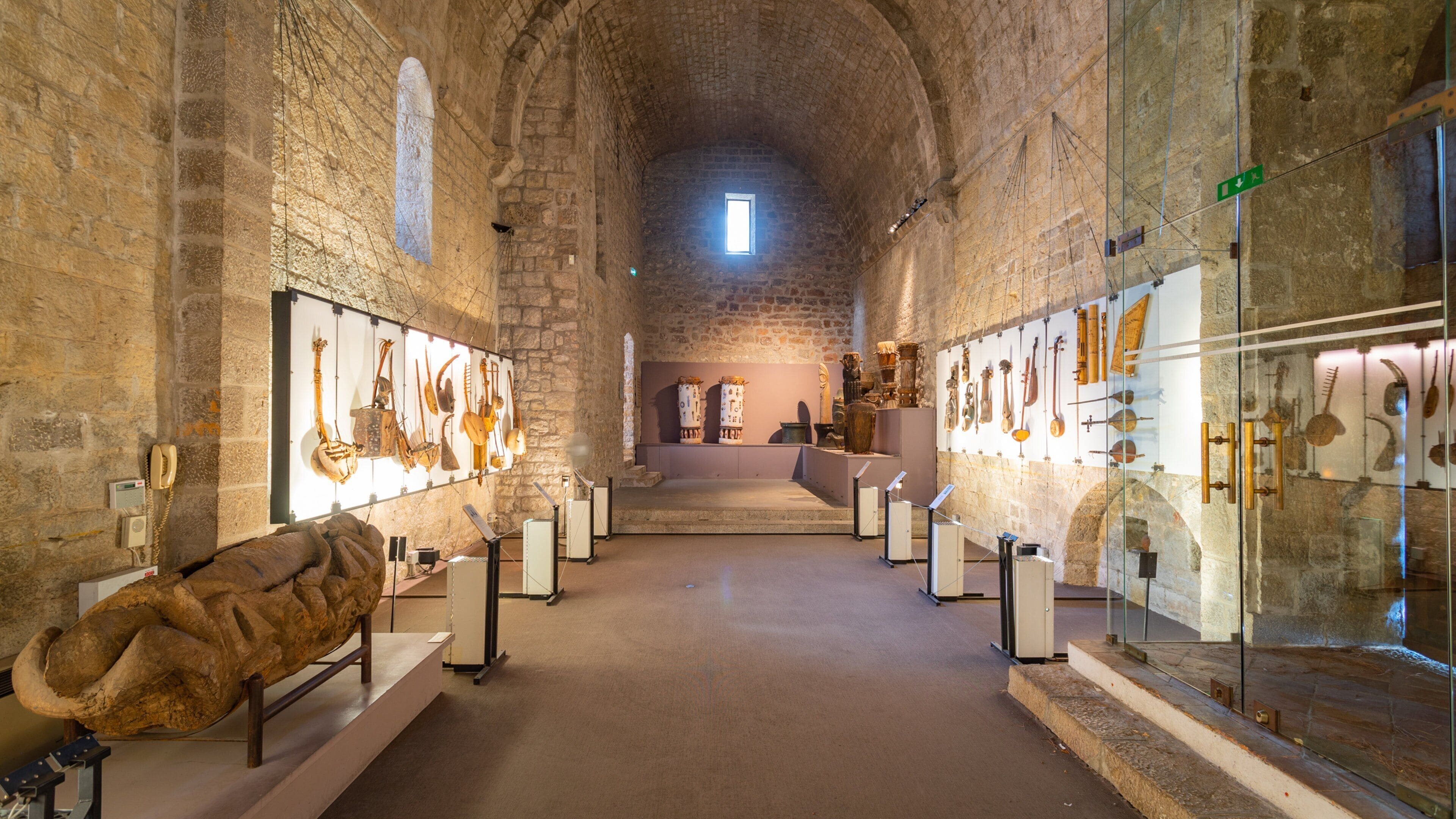 Um corredor de pedra antiga com exposições de artefatos históricos e uma grande escultura em pedra.