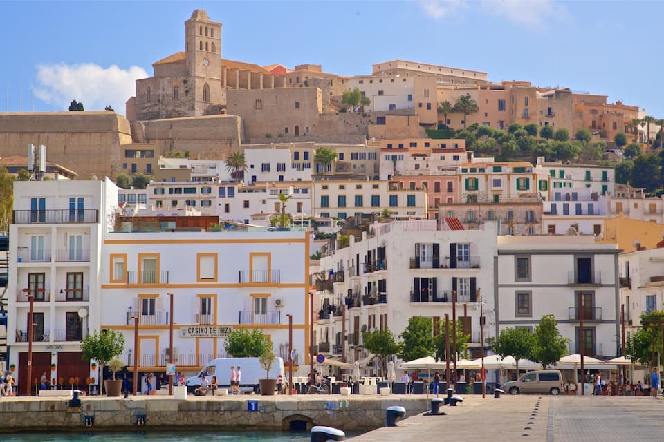 Uma vila costeira com edifícios históricos, uma torre imponente e um casino.