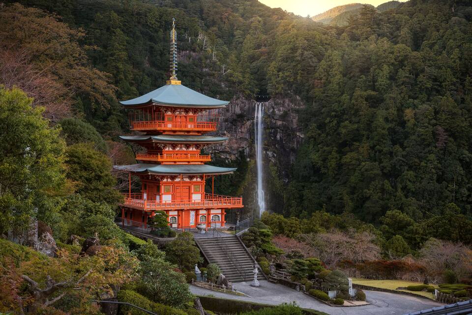 Um pagode de vários níveis com uma cascata ao fundo.