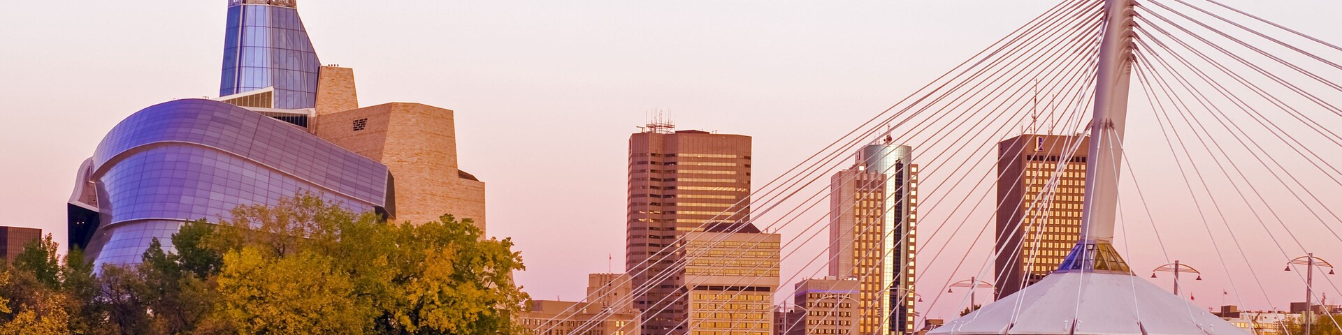 Um horizonte urbano moderno com uma ponte marcante e um edifício único com fachada de vidro curvo.