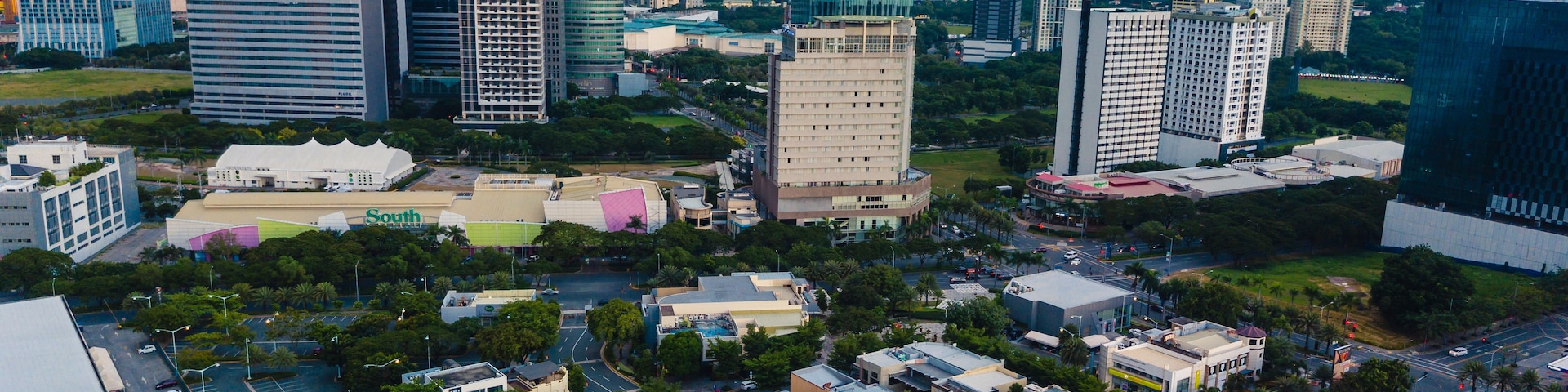 Paisagem urbana com edifícios modernos altos, um estádio e um rio ao fundo.