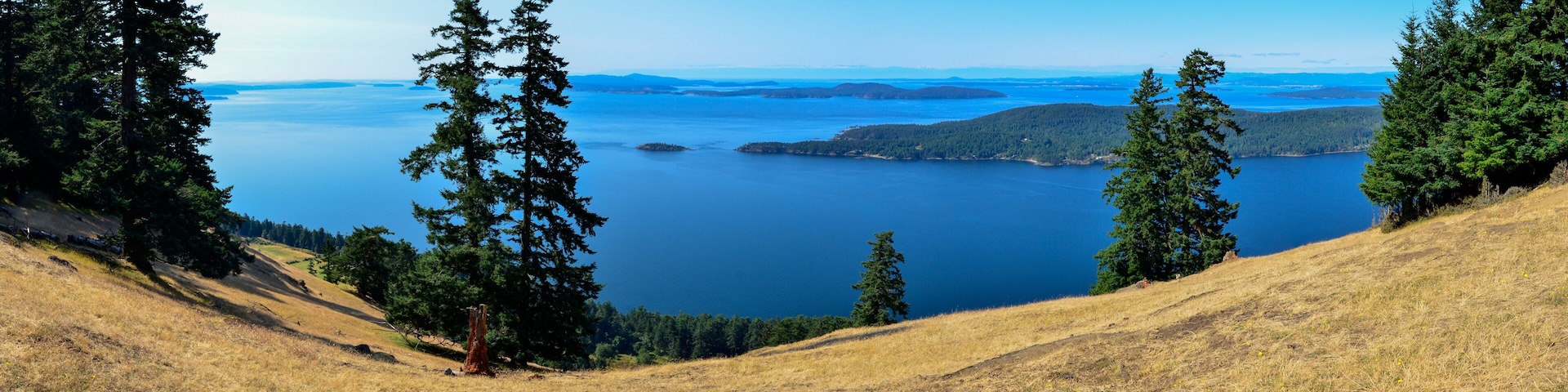 Paisagem montanhosa com vista ampla de um lago grande rodeado por florestas densas.