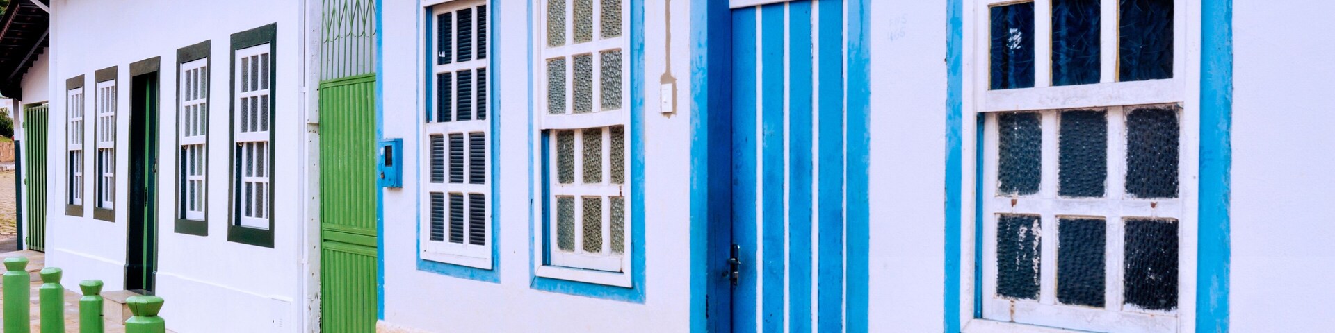 Um edifício branco com detalhes azuis e toldos verdes.