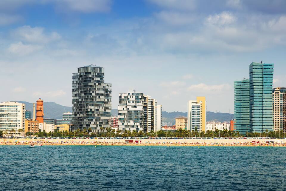 Paisagem costeira urbana com edifícios modernos, uma praia e céu claro.