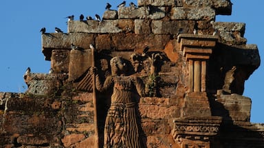 Estrutura de pedra com esculturas de figuras e pássaros empoleirados.
