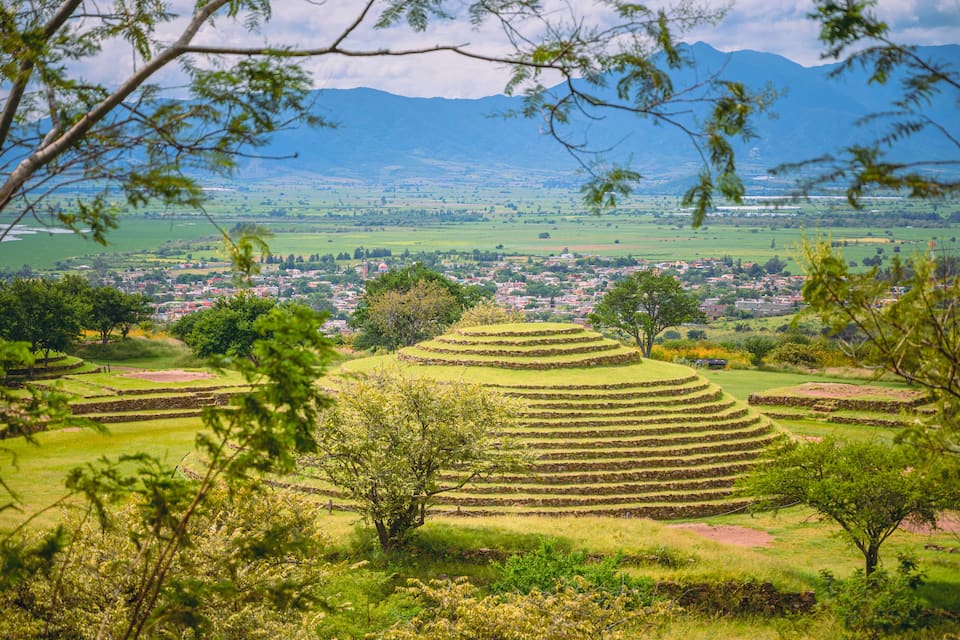 Campos em socalcos, uma cidade e montanhas ao fundo.