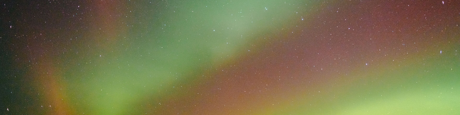 Aurora boreal sobre uma paisagem arborizada.