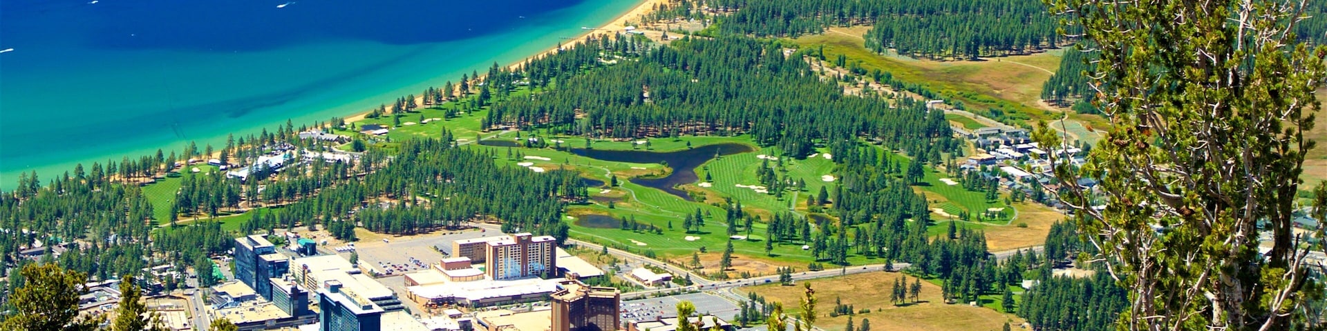 Uma vila costeira com campo de golfe, edifícios e uma área arborizada.