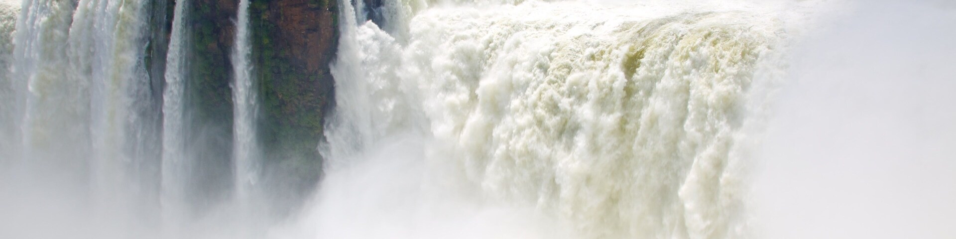 Uma grande cachoeira com múltiplas quedas d'água, rodeada por vegetação exuberante e um céu límpido.
