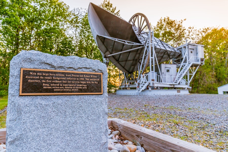 Um grande radiotelescópio com uma placa em frente.