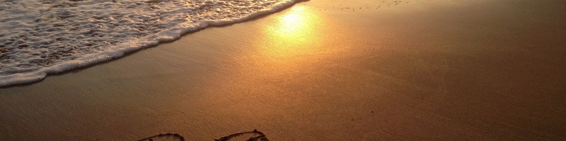 Uma praia com a frase 'Pura Vida' escrita na areia.