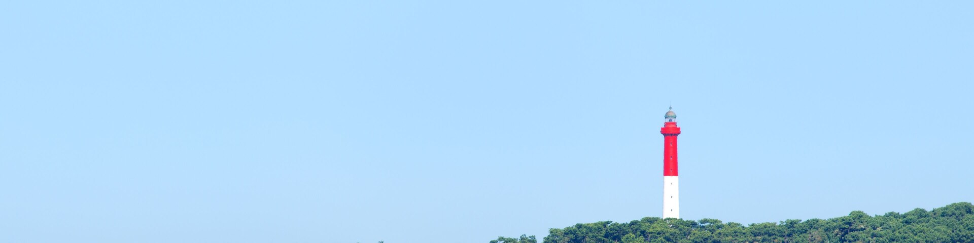 Um farol numa pequena ilha rodeada por águas calmas e vegetação.