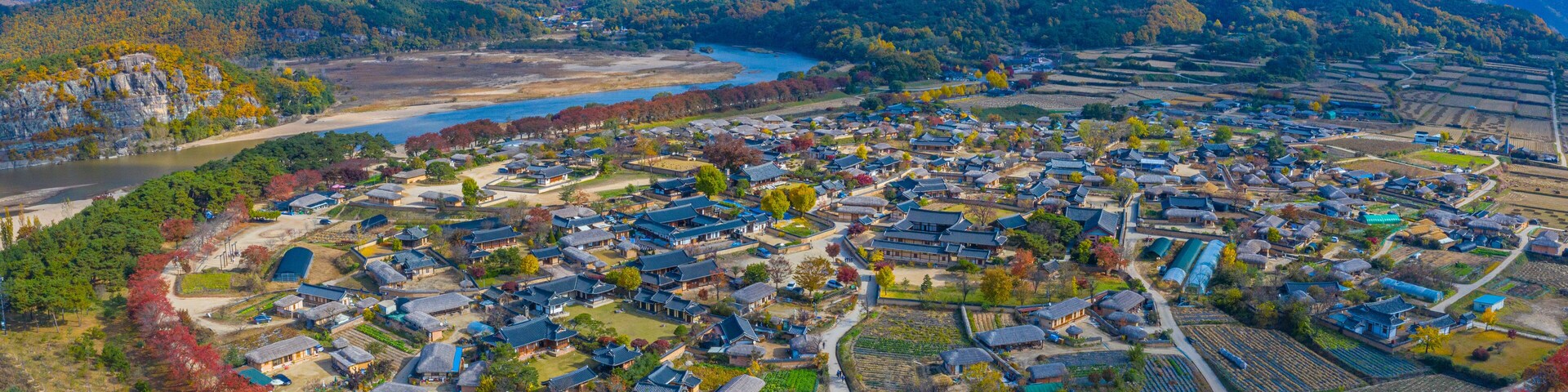 Uma cidade montanhosa com casas tradicionais, um rio e folhagem de outono.
