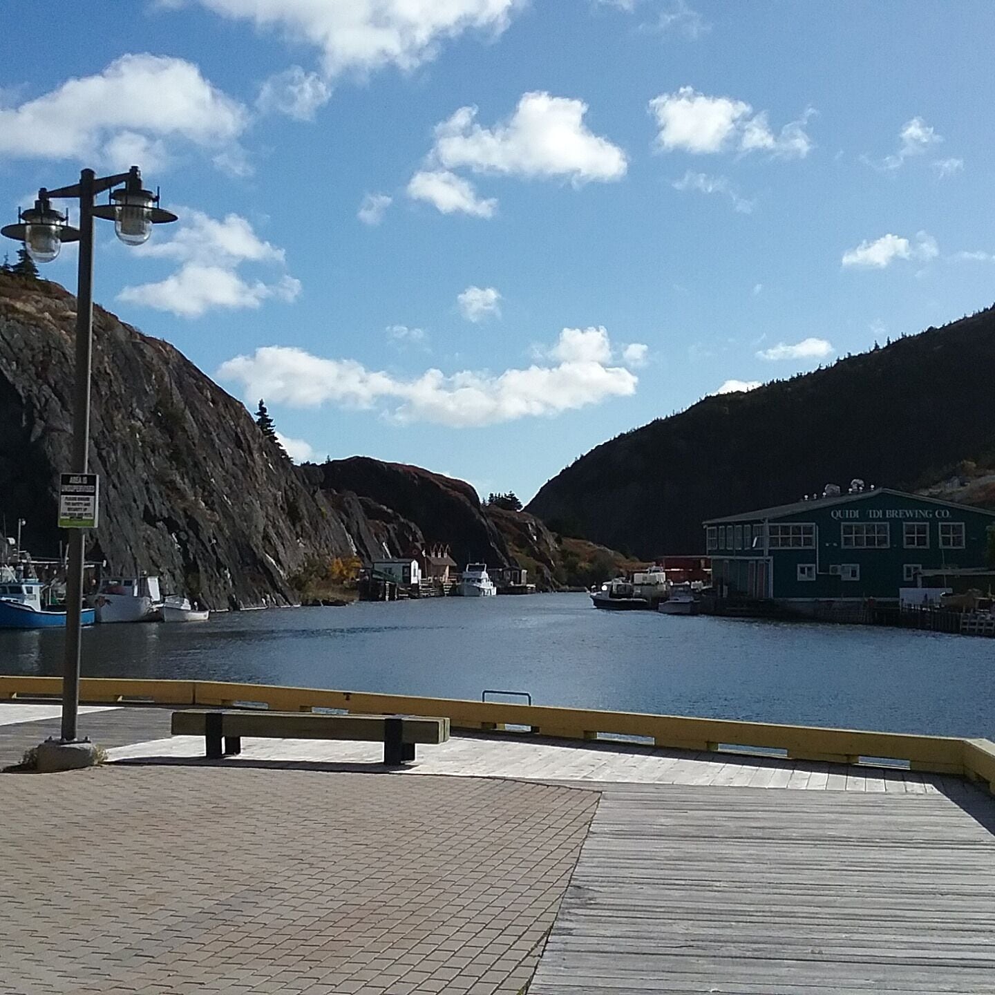 Um porto com barcos, um cais e um edifício com a inscrição 'QUIDI TDI BREWING CO'.