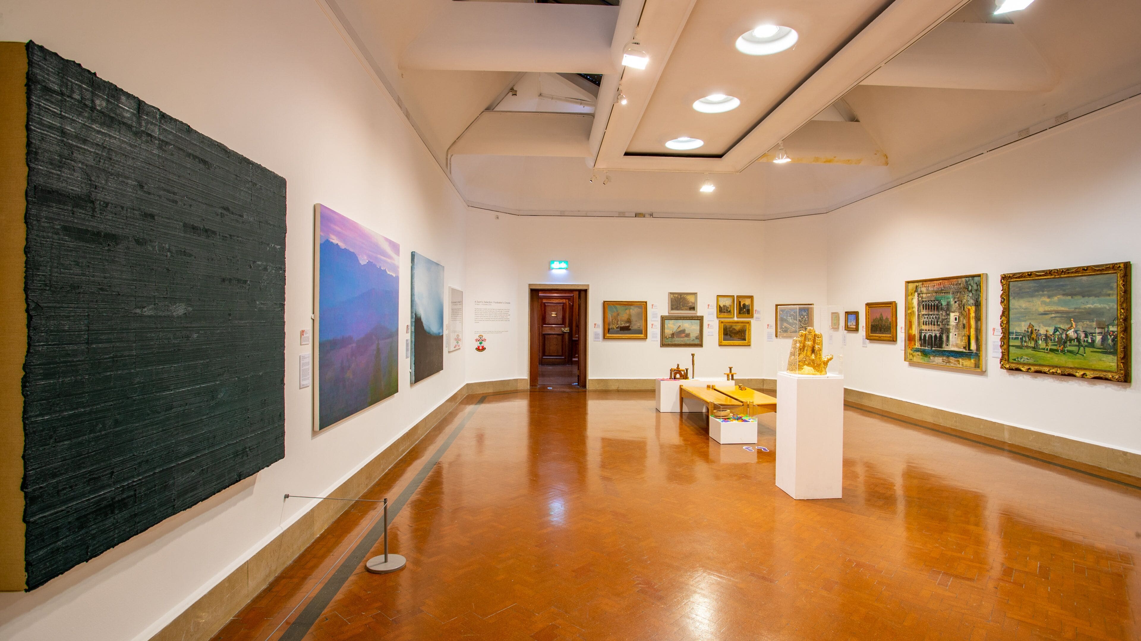 Uma galeria de arte com pinturas e esculturas expostas.