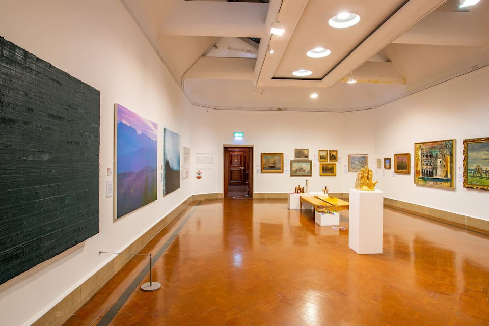 Uma galeria de arte com pinturas e esculturas expostas.