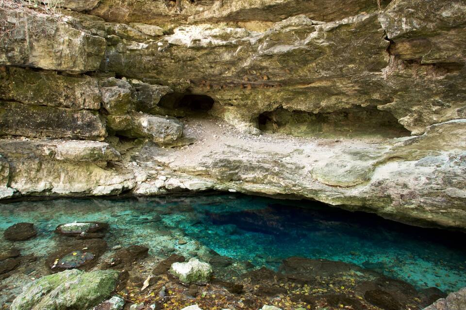Caverna com água cristalina e formações rochosas.