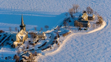 Paisagem coberta de neve com uma igreja, um edifício grande e uma casa pequena.