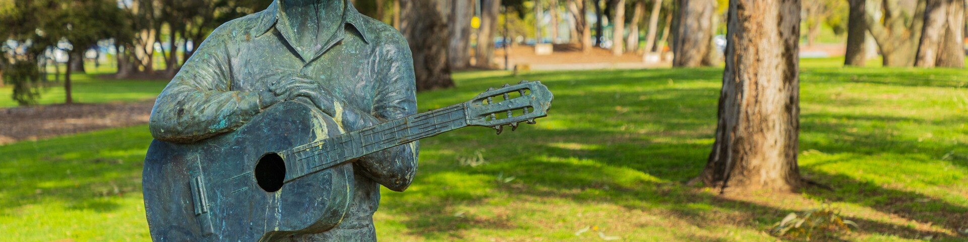 Uma estátua de bronze de um homem com chapéu de cowboy tocando guitarra, com uma placa que diz "Buddy Williams & Agradecimentos a muitos fãs e artistas".