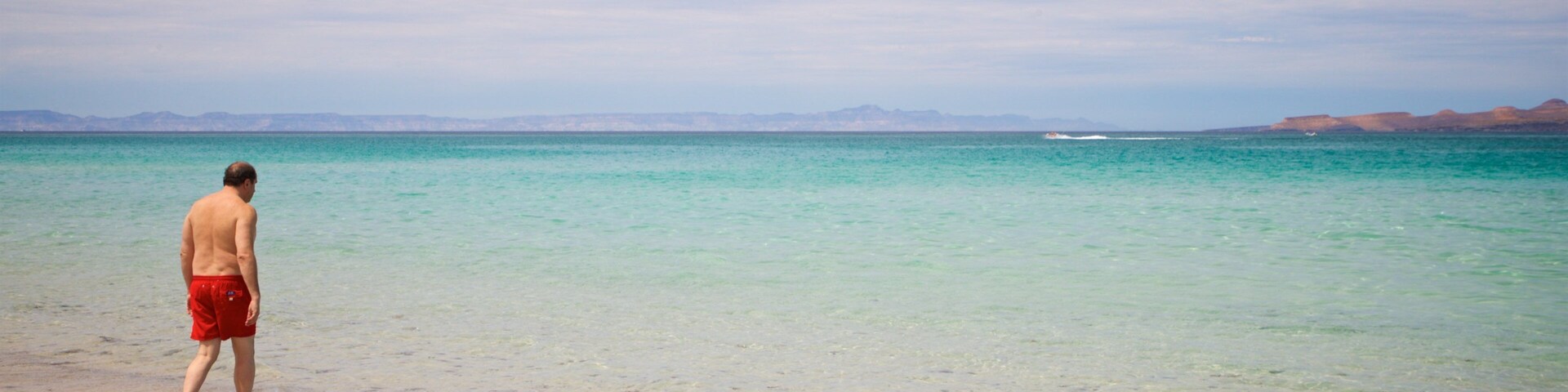 El Tecolote Beach which includes general coastal views and a sandy beach as well as an individual male