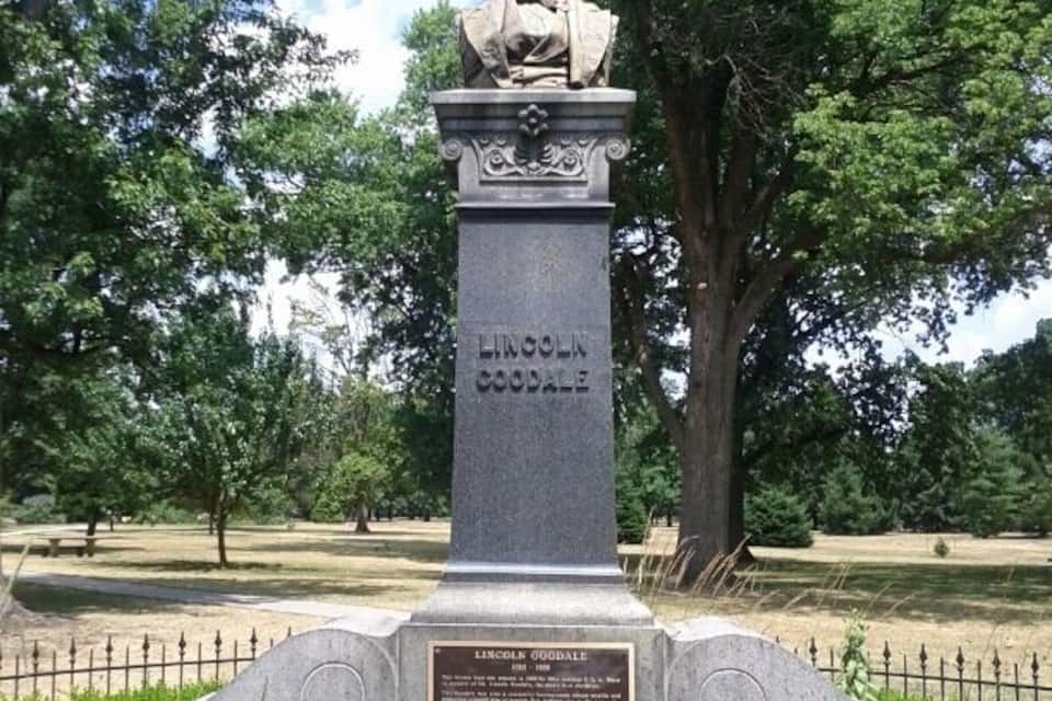 Estátua em homenagem a Lincoln Goodale em um parque com árvores e uma cerca.