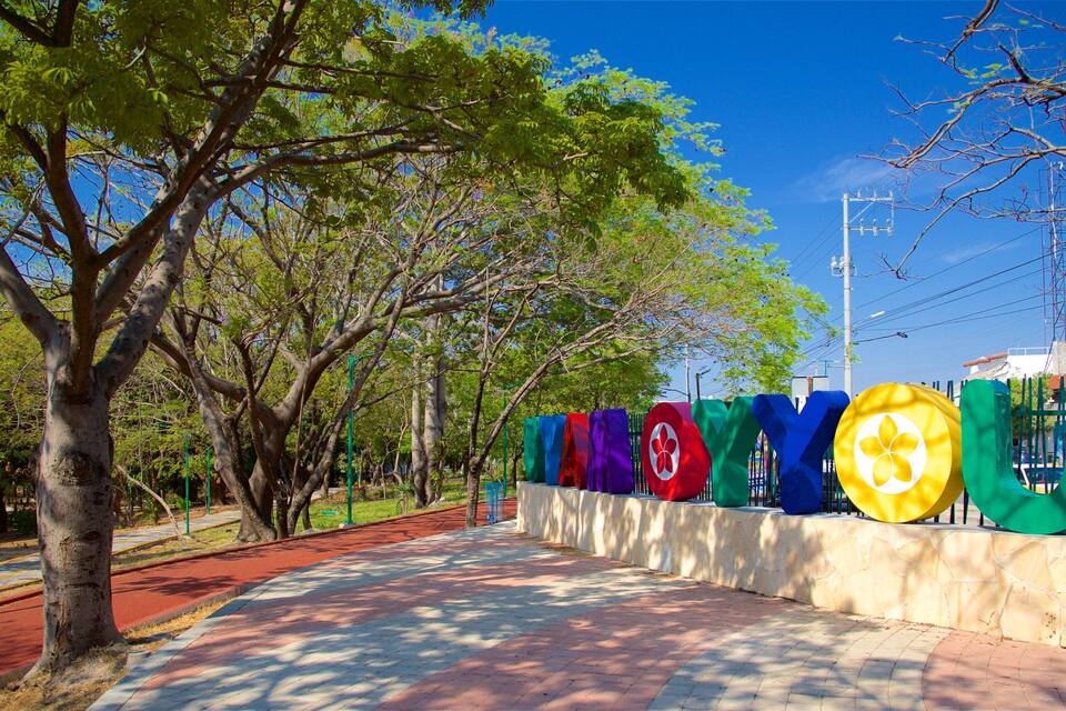 Uma passarela pavimentada, ladeada por bandeiras coloridas e árvores.
