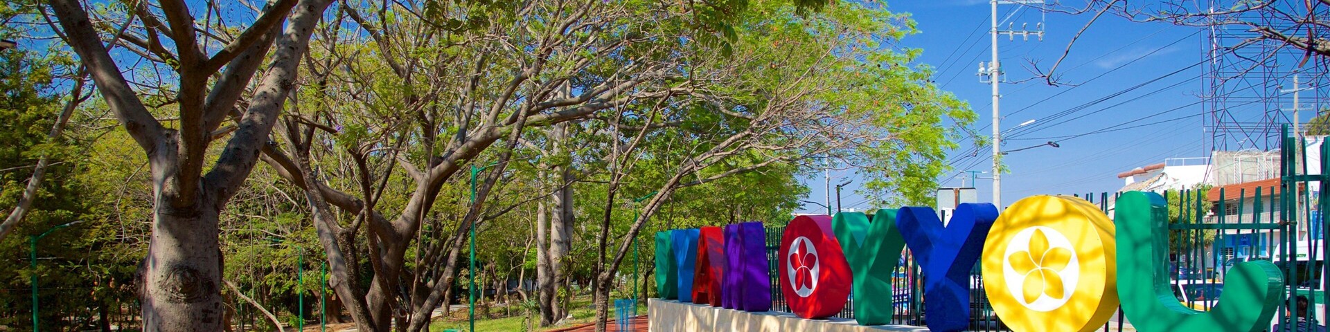 Uma passarela pavimentada, ladeada por bandeiras coloridas e árvores.