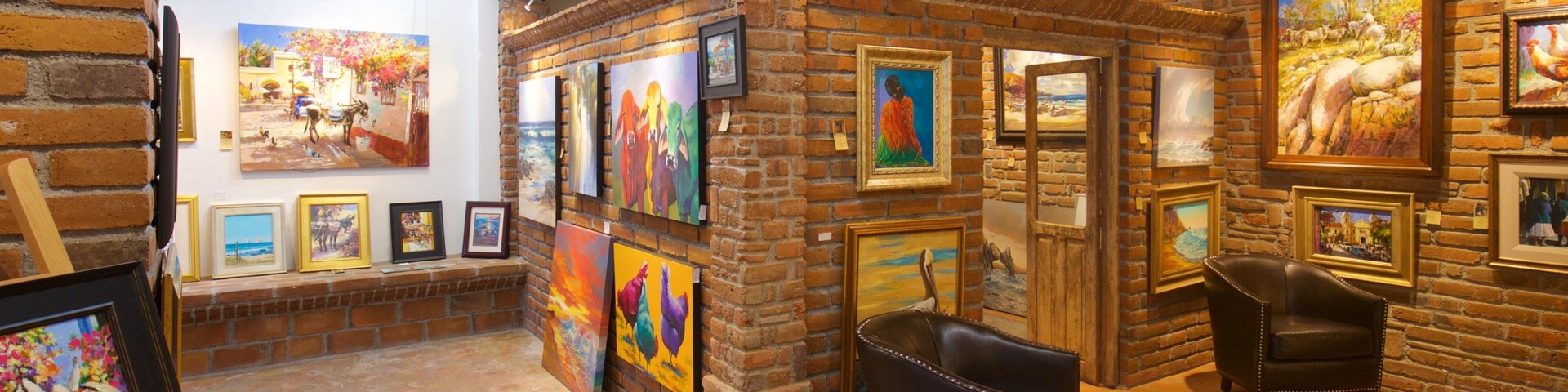 Uma galeria de arte com paredes de tijolo e diversas pinturas expostas.