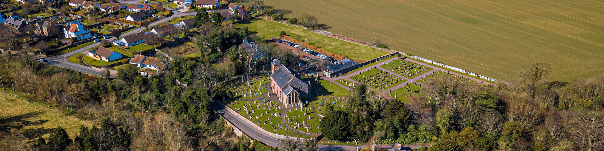 Vista aérea de uma aldeia com casas, uma igreja e um cemitério.