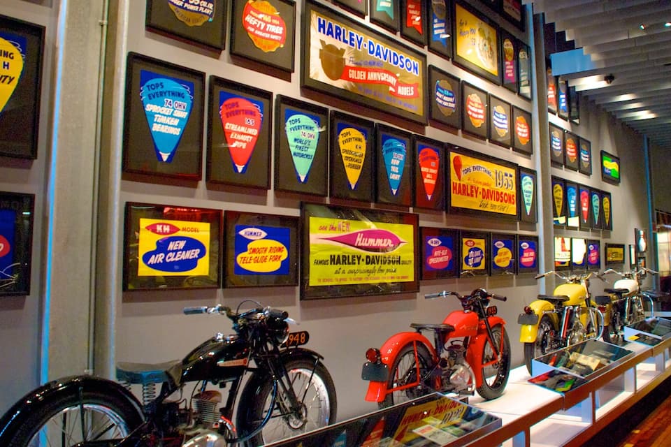 Uma parede com anúncios e modelos de motocicletas antigas.