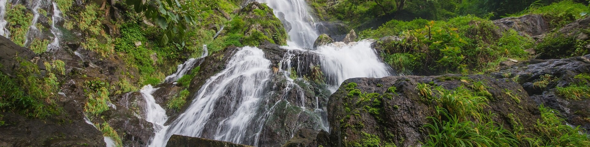 Uma cascata descendo sobre rochas em uma floresta verde e exuberante.