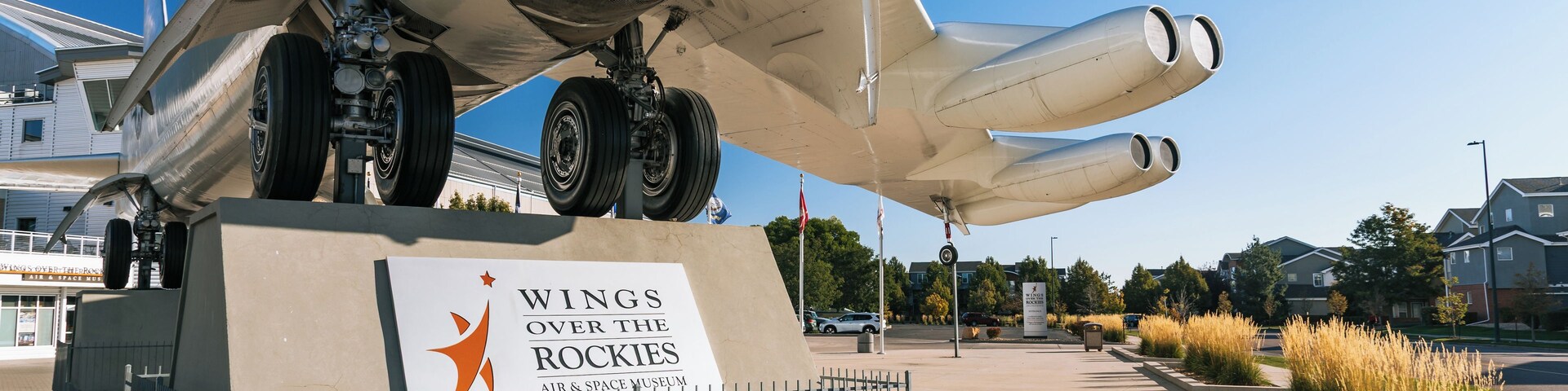 Uma grande asa de aeronave em exibição, com uma placa indicando 'Wings Over the Rockies Air & Space Museum'.
